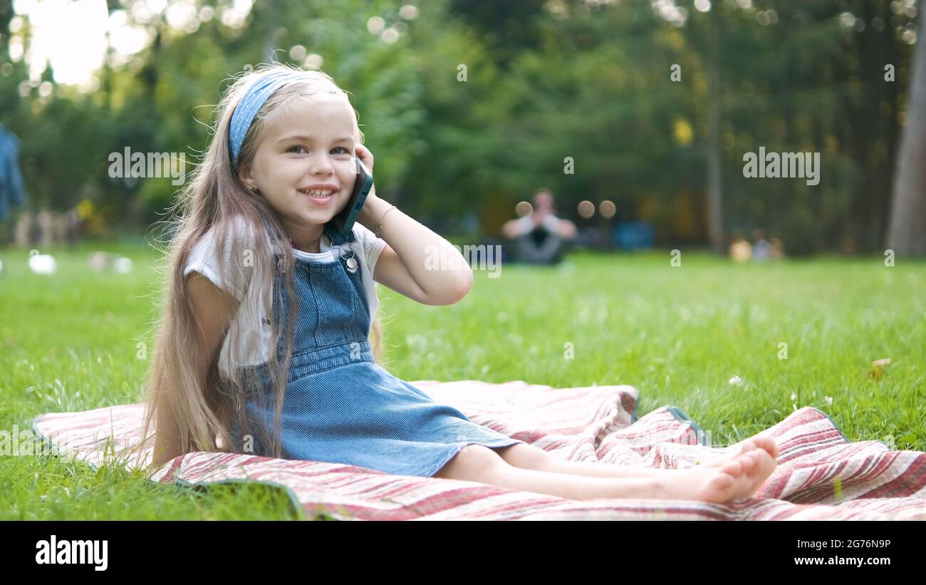 Positive little child girl having conversation on her mobile phone in ...