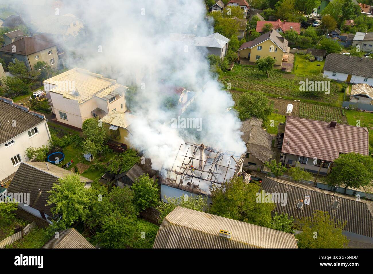 Aerial view of a house on fire with orange flames and white thick smoke ...