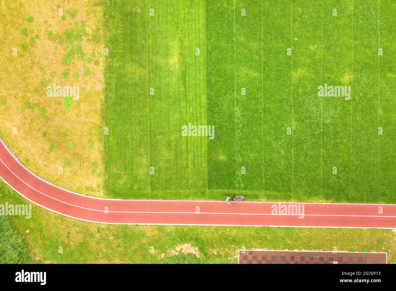 Aerial view of small figure of worker cutting green grass with mowing ...