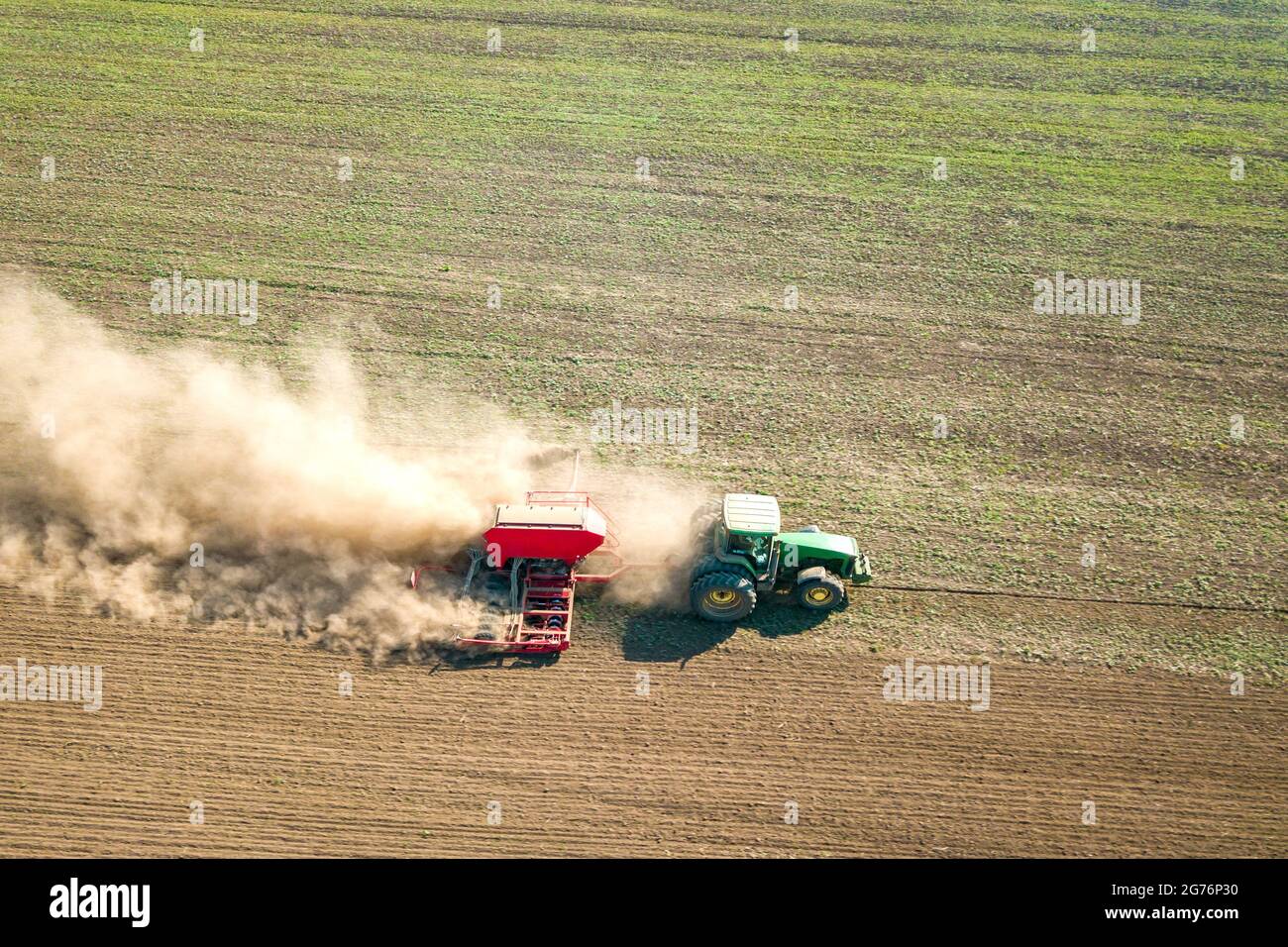 Top down aerial view of green tractor cultivating ground and seeding a ...