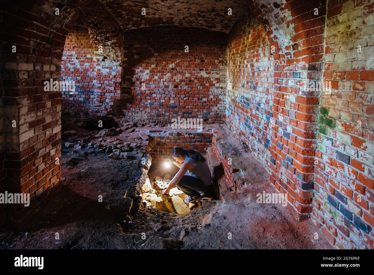 Archaeologist with flashlight examines the old crypt under church Stock ...