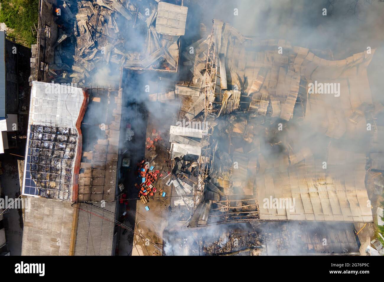 Aerial view of ruined building on fire with collapsed roof and rising ...
