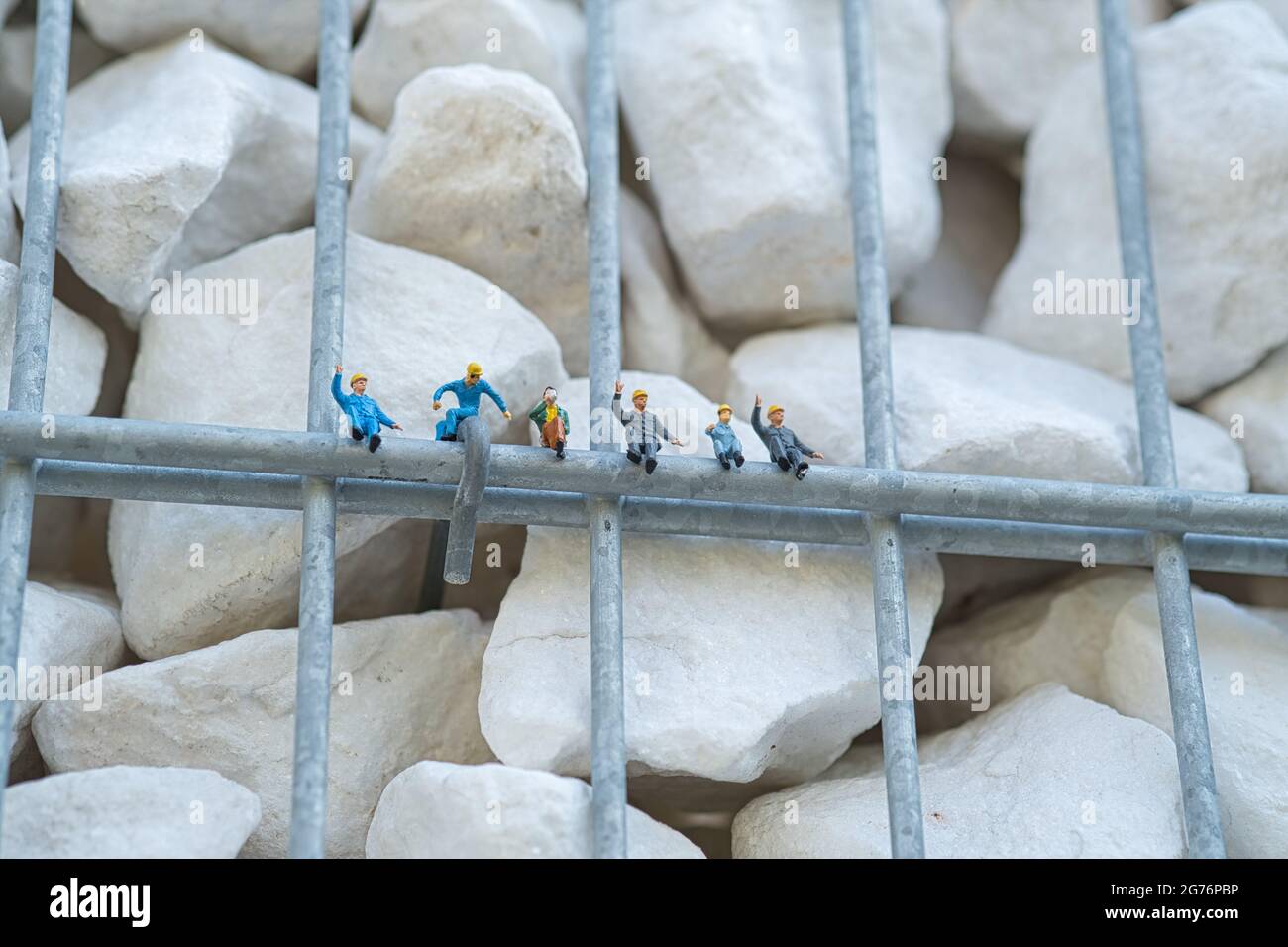 The miniature figures as workers team on the metal cage Stock Photo - Alamy