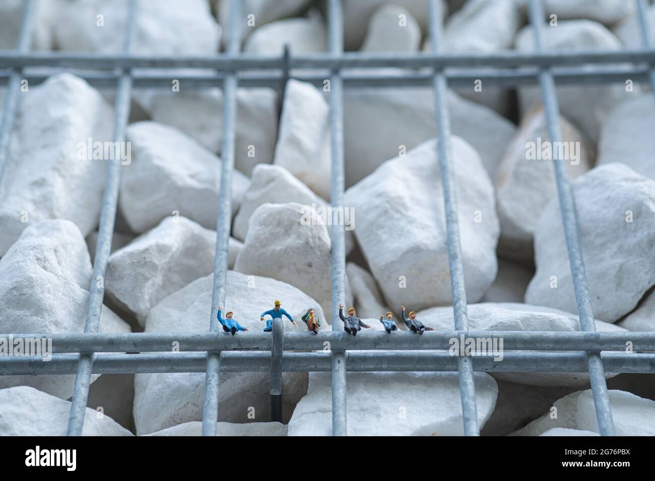 The miniature figures as workers team on the metal cage Stock Photo - Alamy