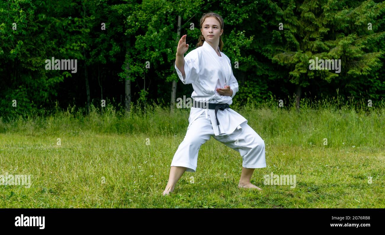 teenage girl practicing karate kata outdoors, performs soto uke or ...