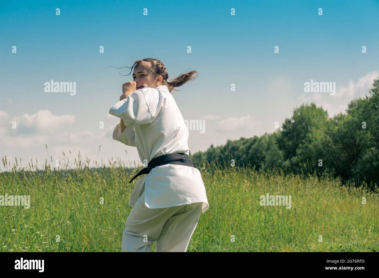 teenage girl practicing karate kata outdoors, prepares to uro mawashi ...