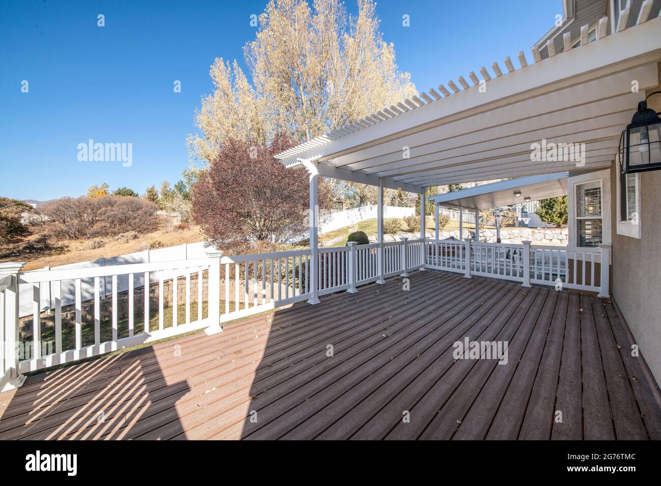 House terrace with wood planks flooring, white handrailings and pergola ...