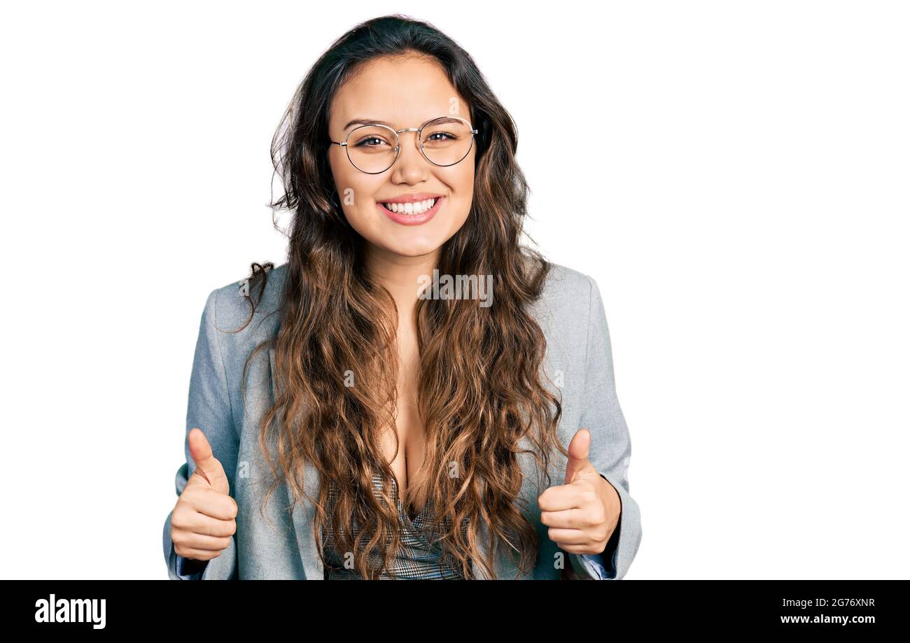 Young hispanic girl wearing business clothes and glasses success sign ...