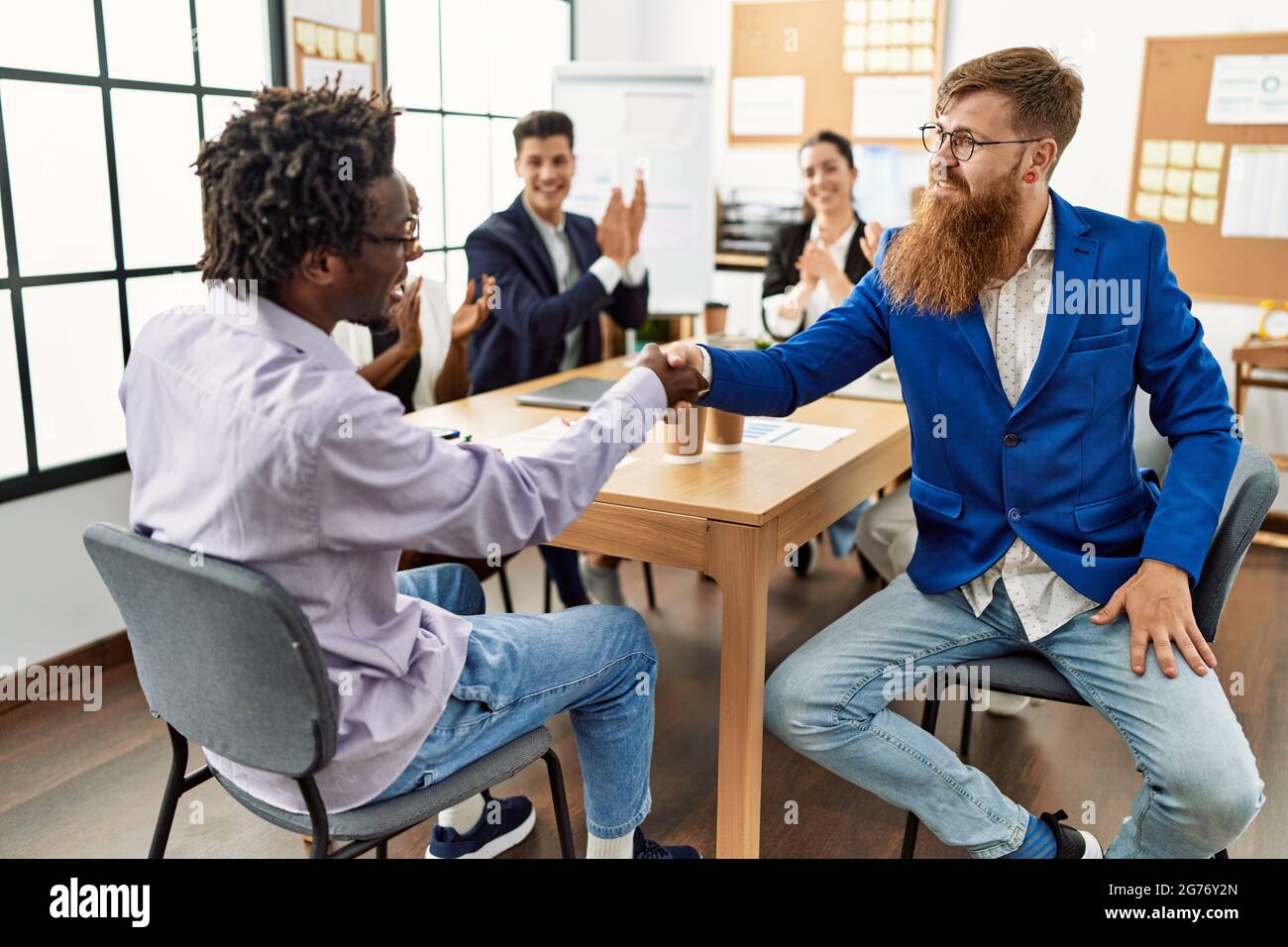 Group of business workers smiling and clapping to partners handshake at ...