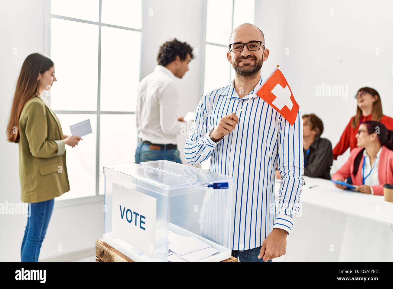 Young swiss voter man smiling happy holding switzerland flag standing ...