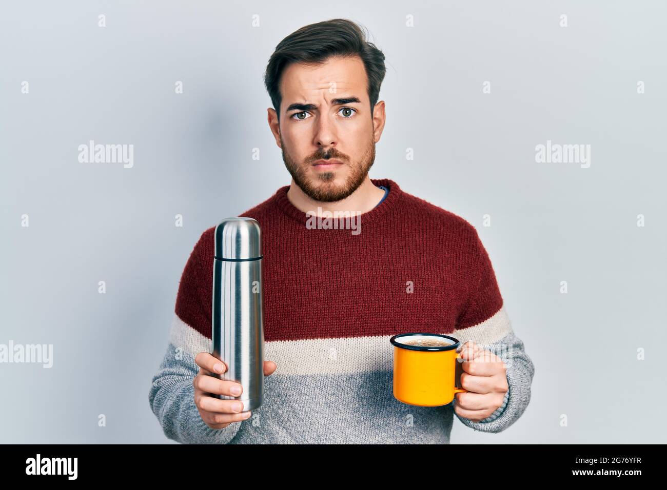 Handsome caucasian man with beard drinking a cup of coffee holding ...