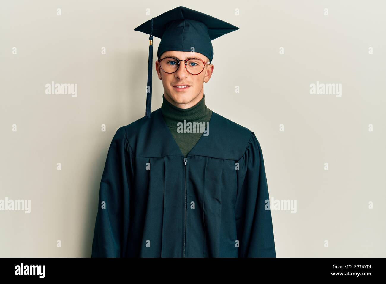 Young caucasian man wearing graduation cap and ceremony robe with a ...