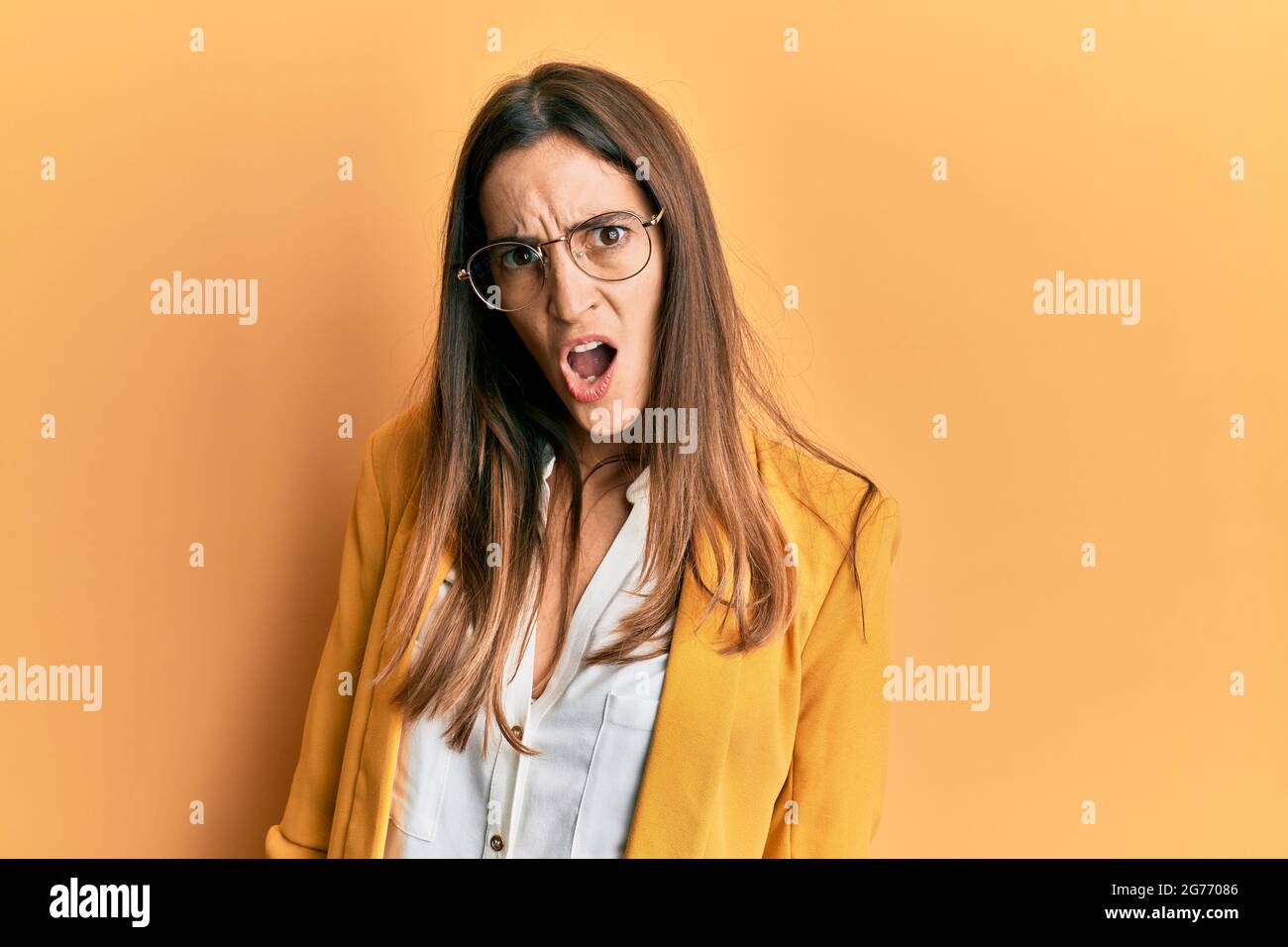 Young beautiful woman wearing business style and glasses in shock face ...