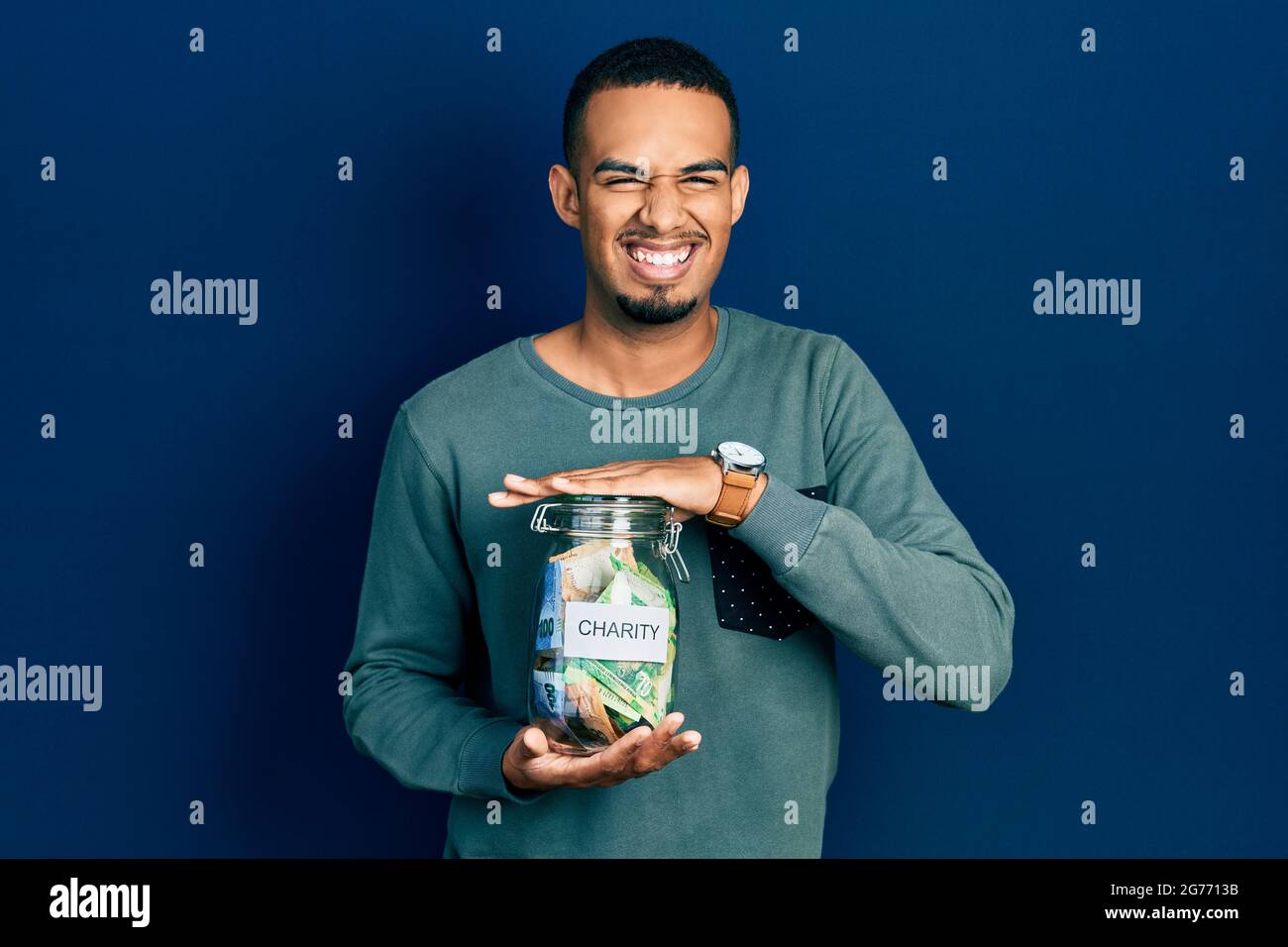 Young african american man holding charity jar with south africa rand ...