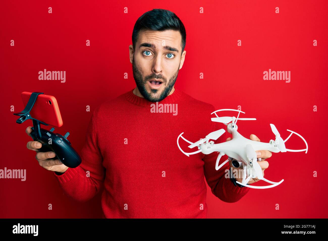 Young hispanic man holding drone and remote control with smartphone in ...