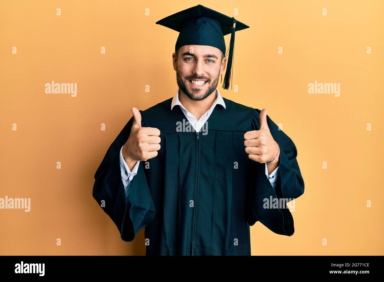 Young hispanic man wearing graduation cap and ceremony robe success ...