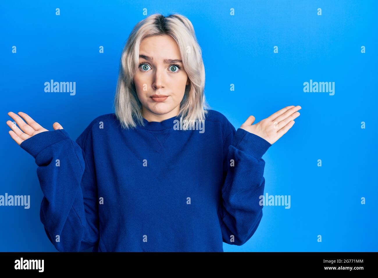 Young blonde girl wearing casual clothes clueless and confused with ...
