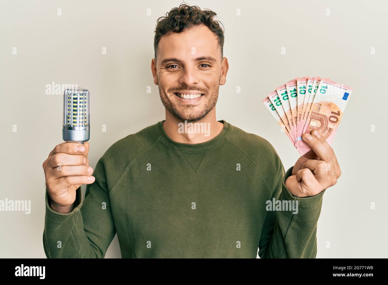Young hispanic man holding led bulb and euros banknotes smiling with a ...