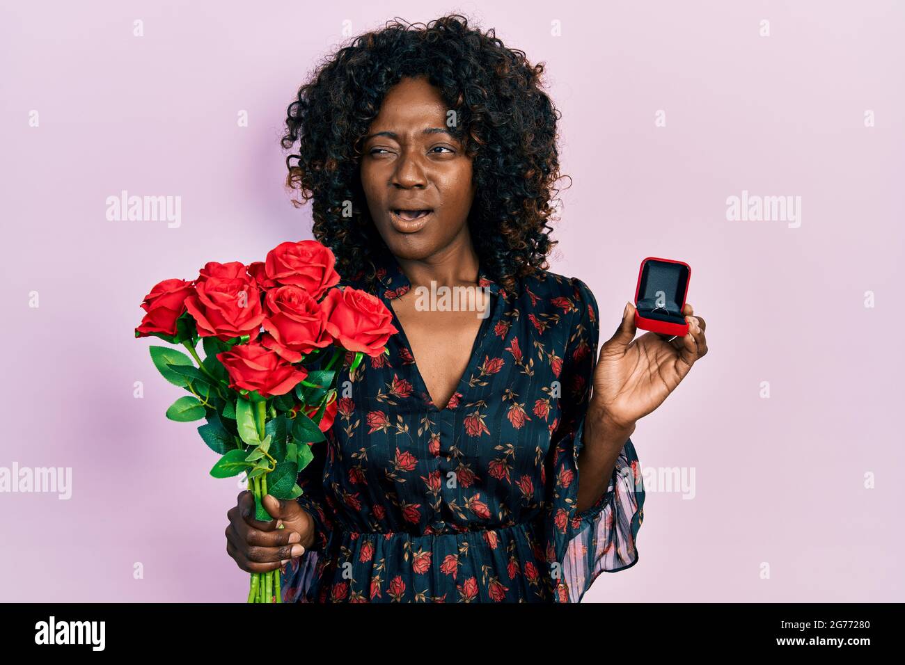 Young african american woman holding bouquet of flowers and engagement ...