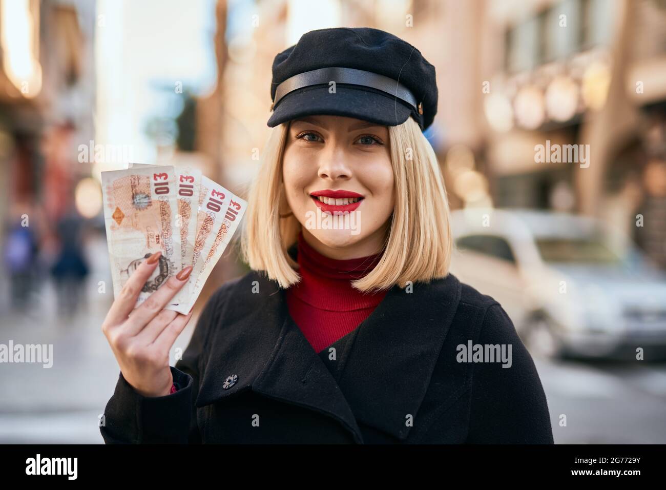 Young blonde woman smiling happy holding united kingdom pounds ...