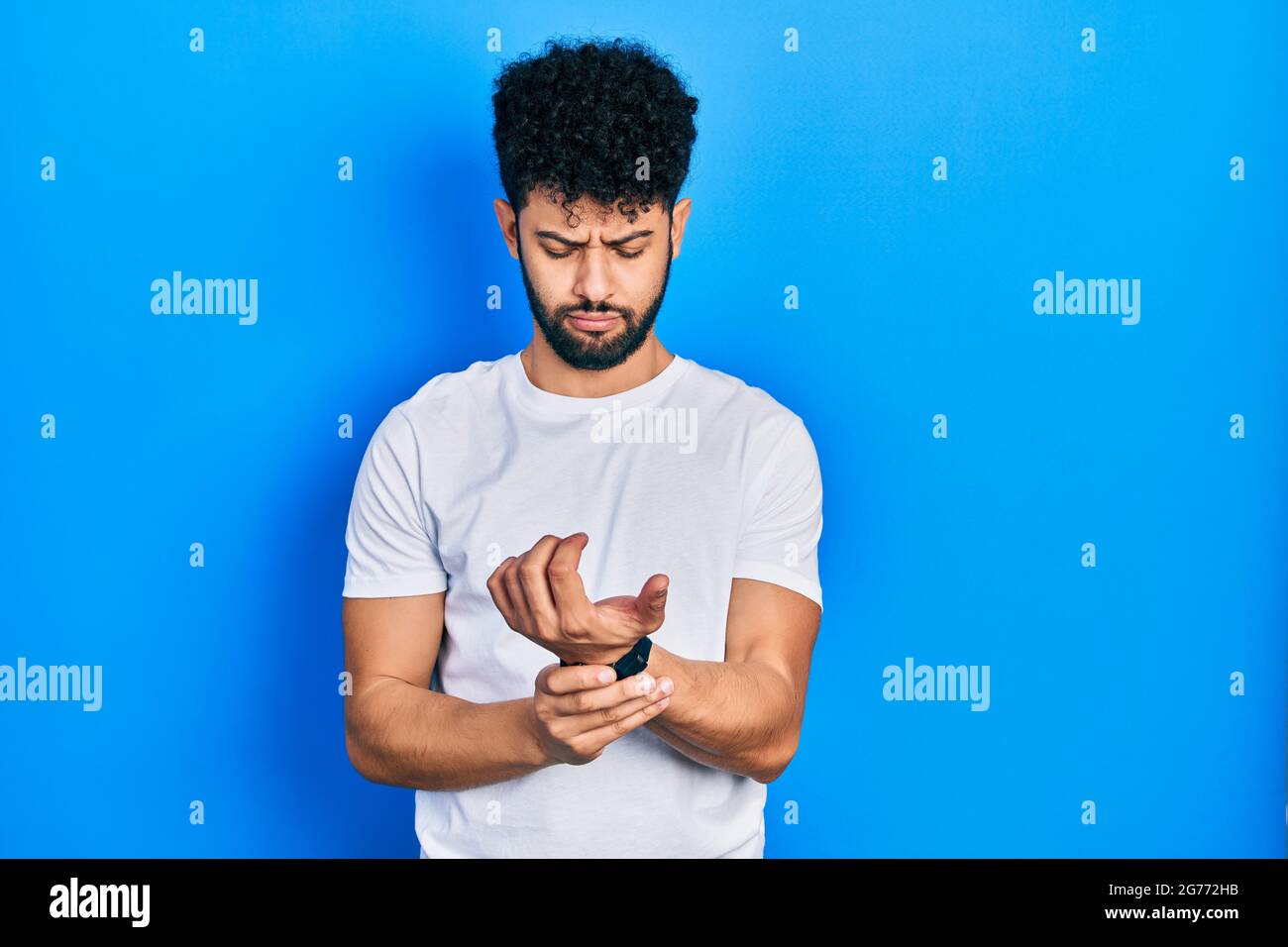 Young arab man with beard wearing casual white t shirt suffering pain ...