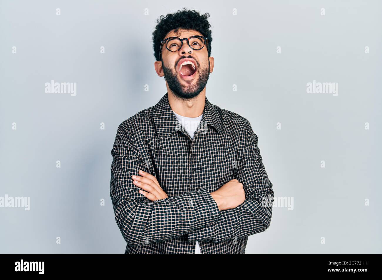 Young arab man with beard wearing glasses with arms crossed gesture ...