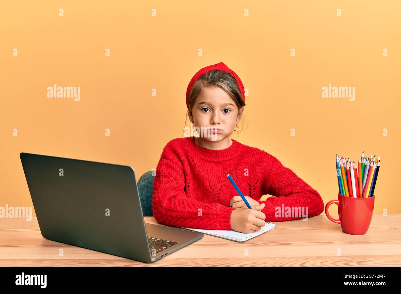 Little beautiful girl studying using computer laptop puffing cheeks ...