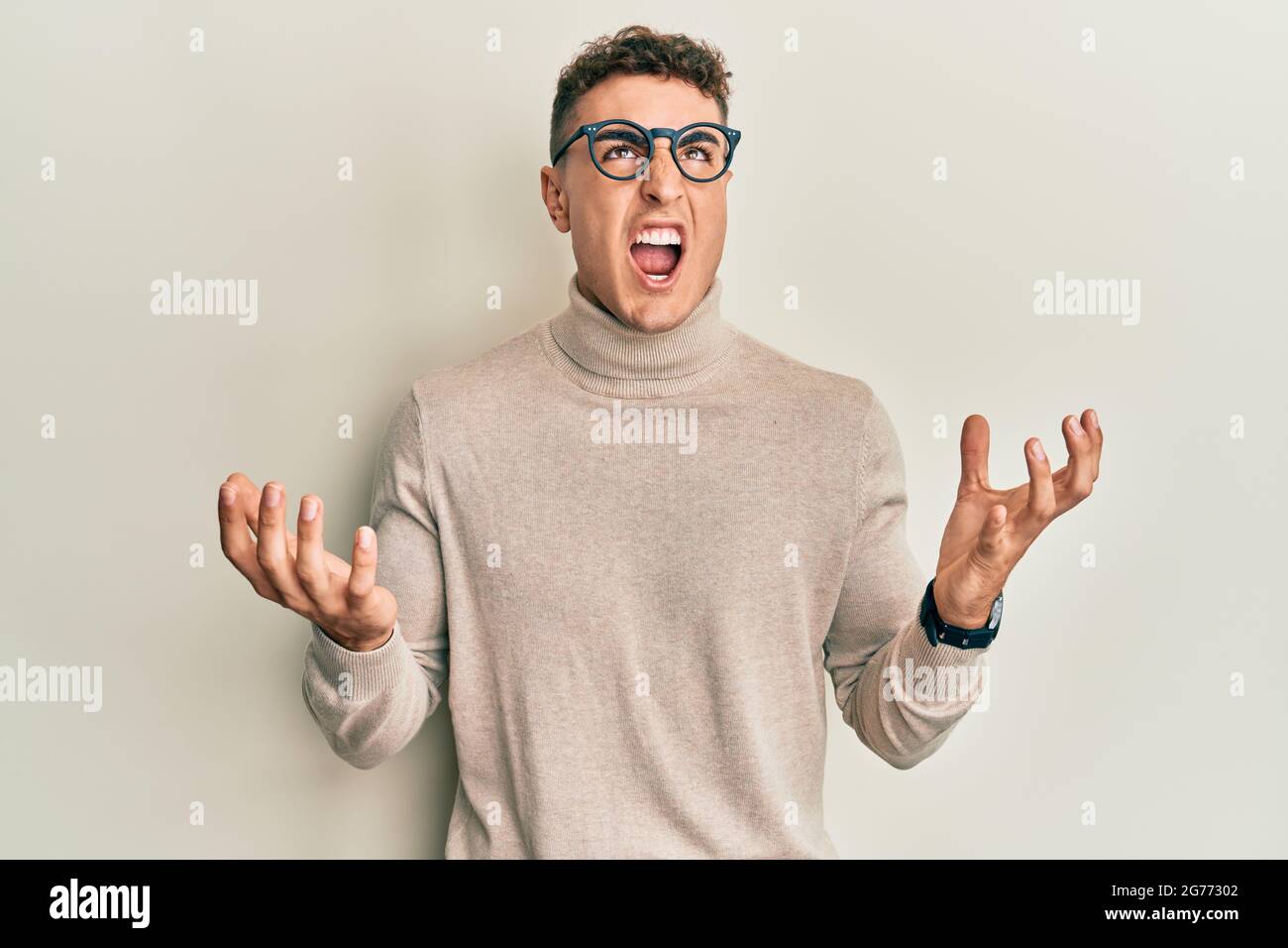 Hispanic young man wearing casual turtleneck sweater crazy and mad ...