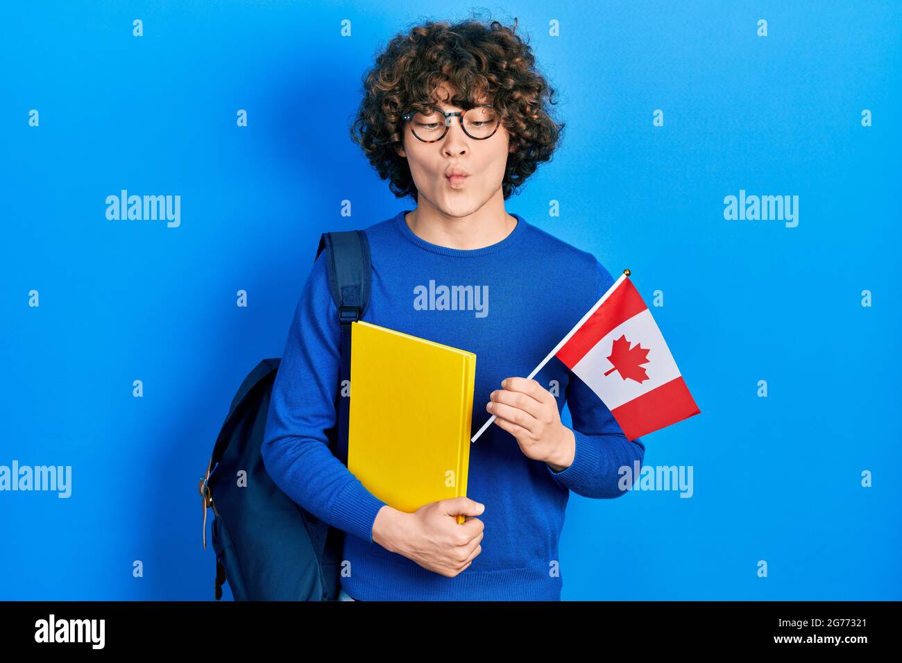 Handsome young man exchange student holding canada flag making fish ...