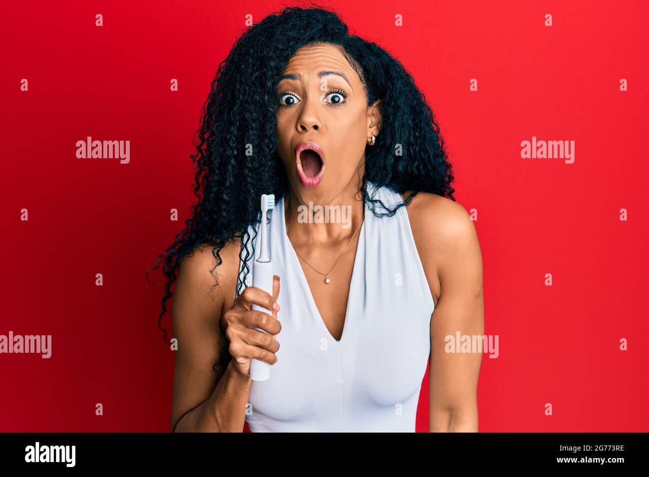 Middle age african american woman holding electric toothbrush scared ...