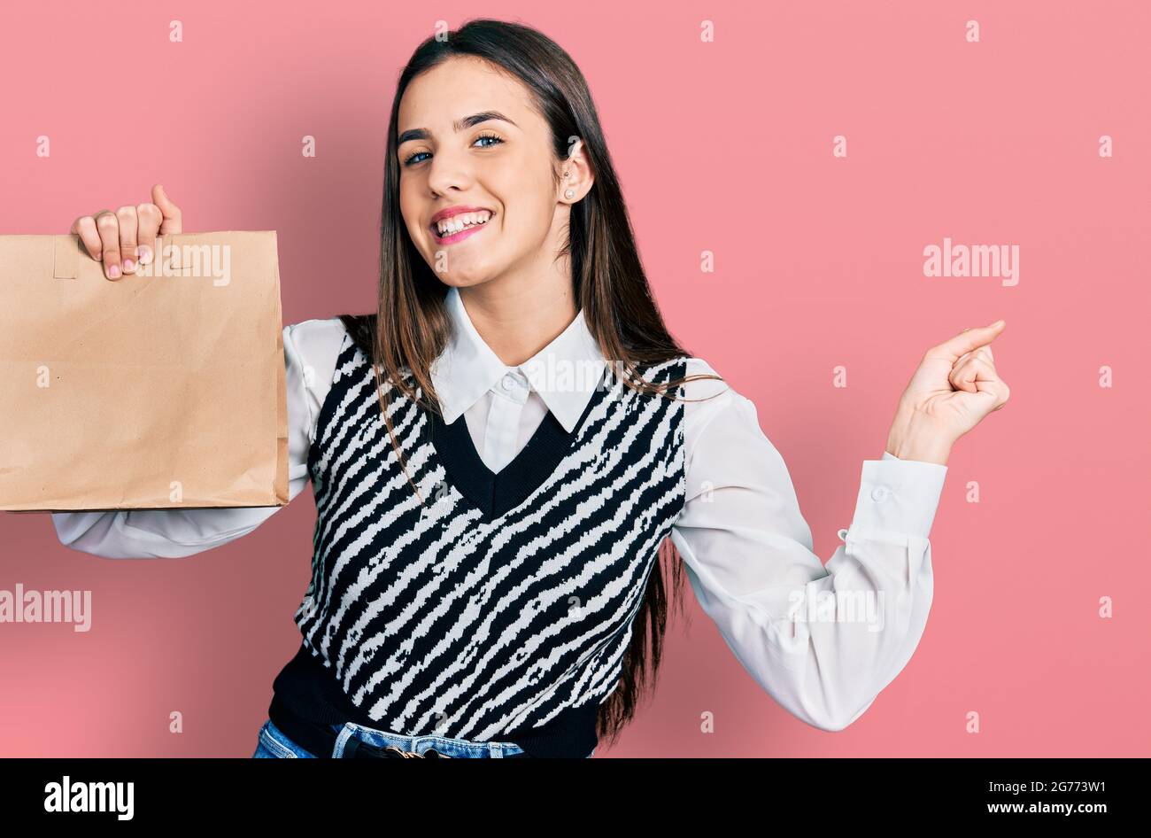 Young brunette teenager holding take away paper bag screaming proud ...