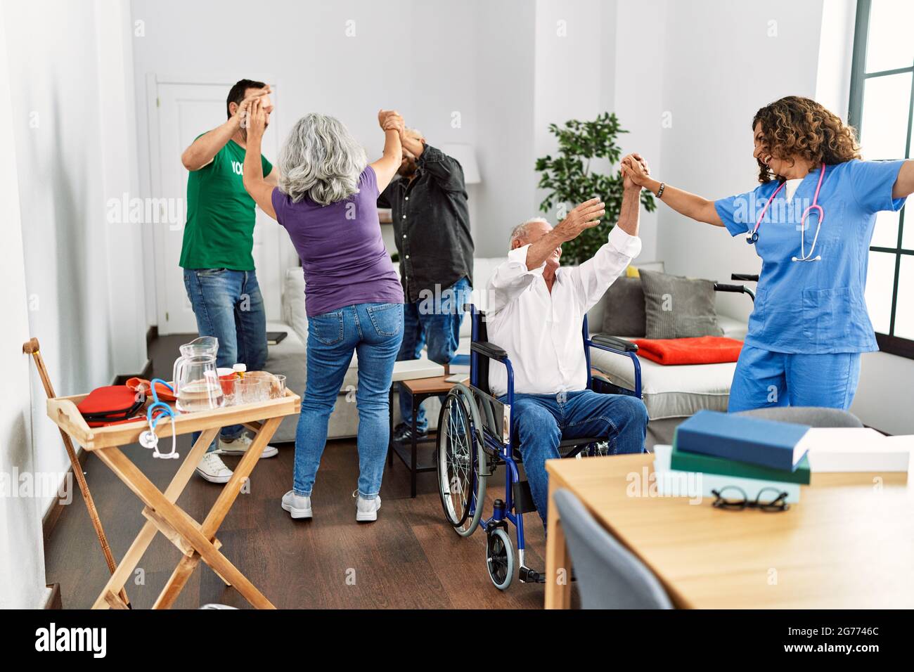 Group of retired people having party dancing with doctor and volunteer ...
