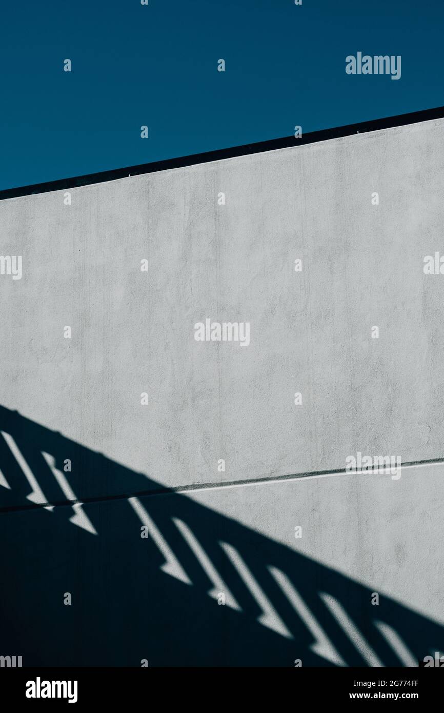 A sleek modern building with a diagonal shadow falling on it under a ...