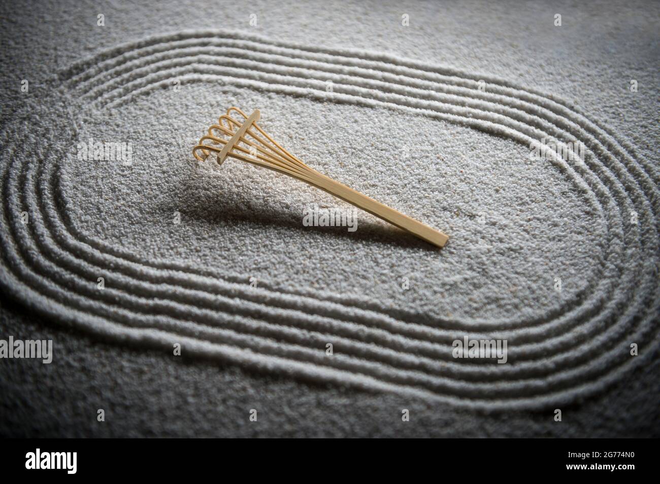 Wooden rake sits on Japanese Zen garden raked with a simple sports ...