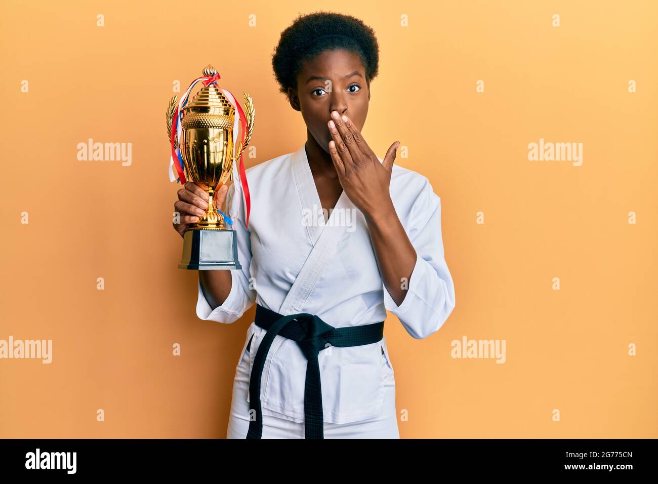 Young african american girl wearing karate kimono holding trophy ...