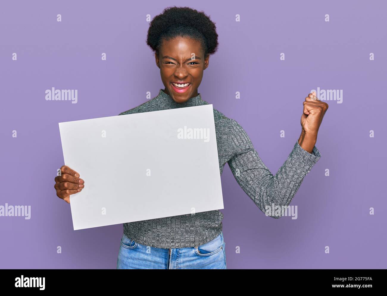 Young african american girl holding blank empty banner screaming proud ...
