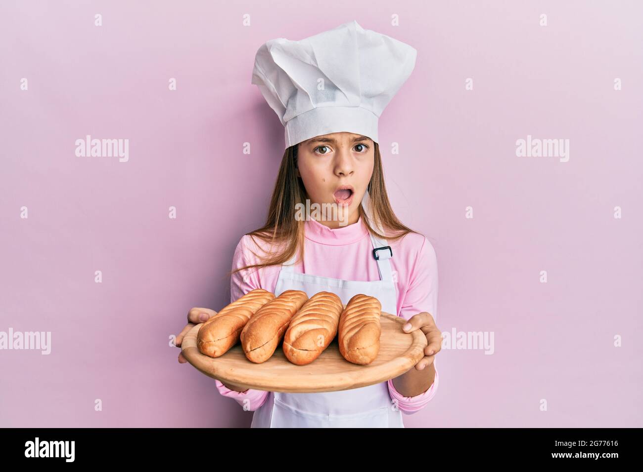 Beautiful brunette little girl wearing baker uniform holding homemade ...