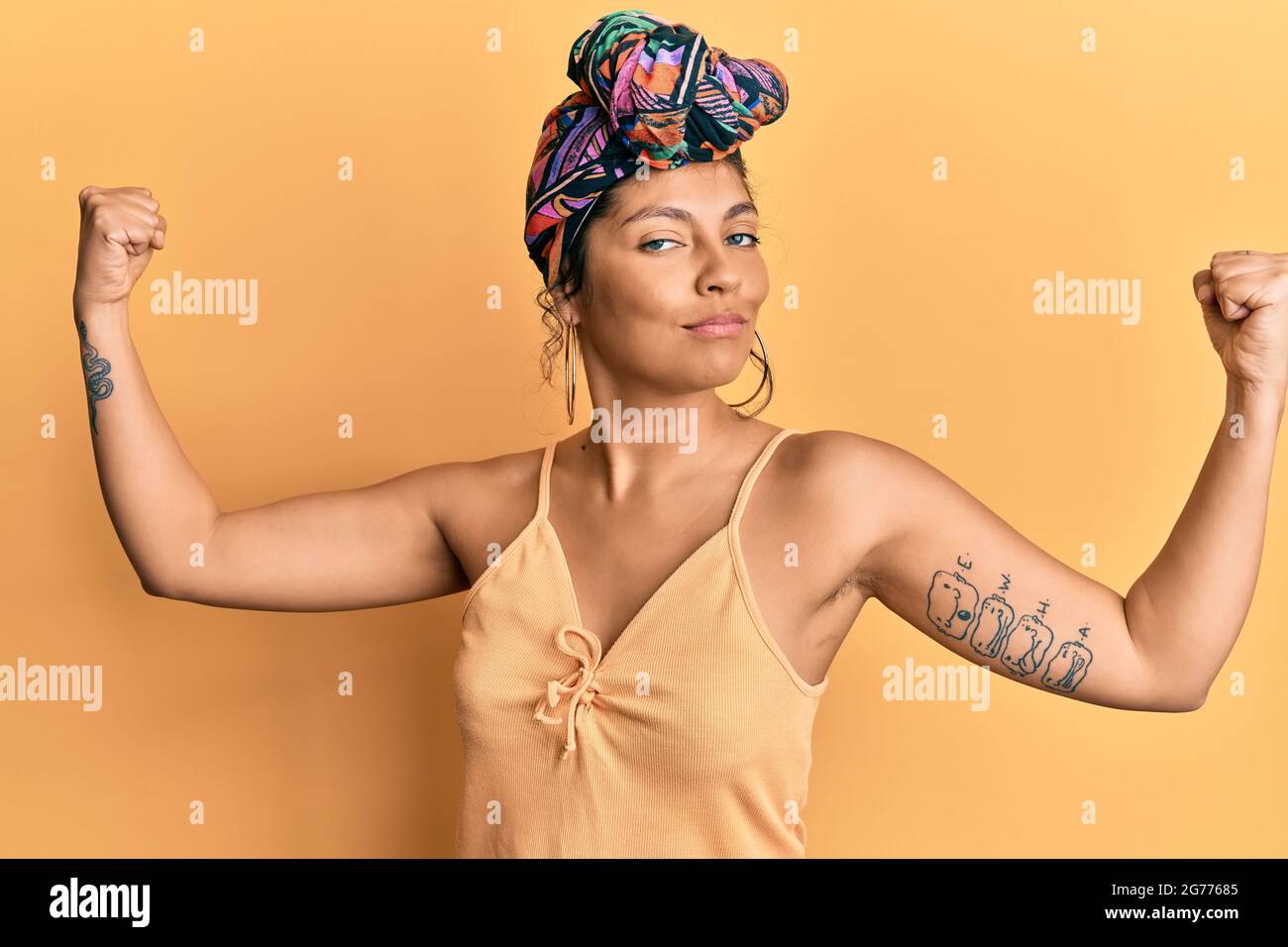 Young hispanic girl wearing hair turban over yellow background showing ...