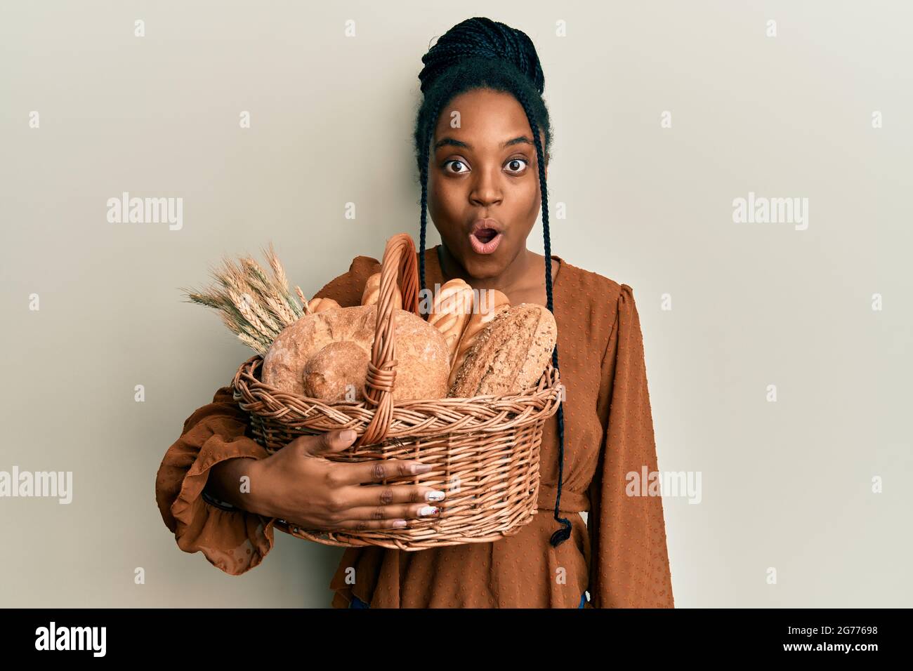 African american woman with braided hair holding wicker basket with ...