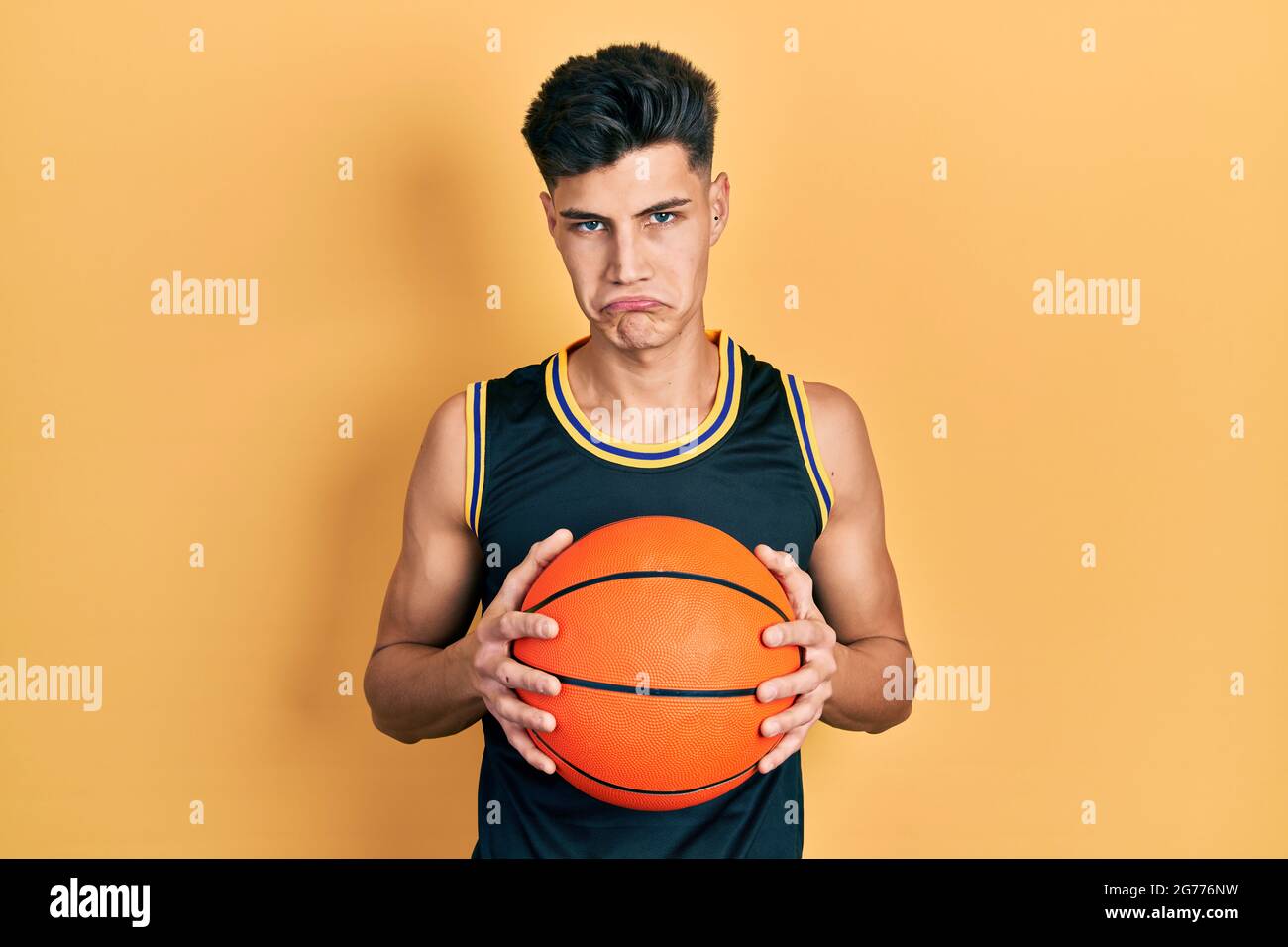 Young hispanic man holding basketball ball depressed and worry for ...