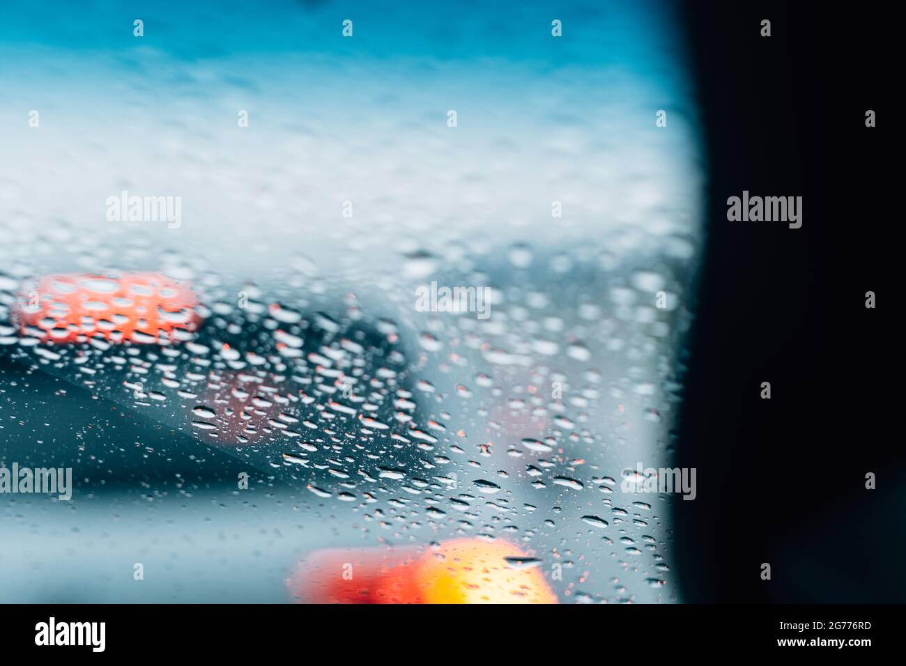 A wet window with red and orange bokeh lights behind the glass in the ...