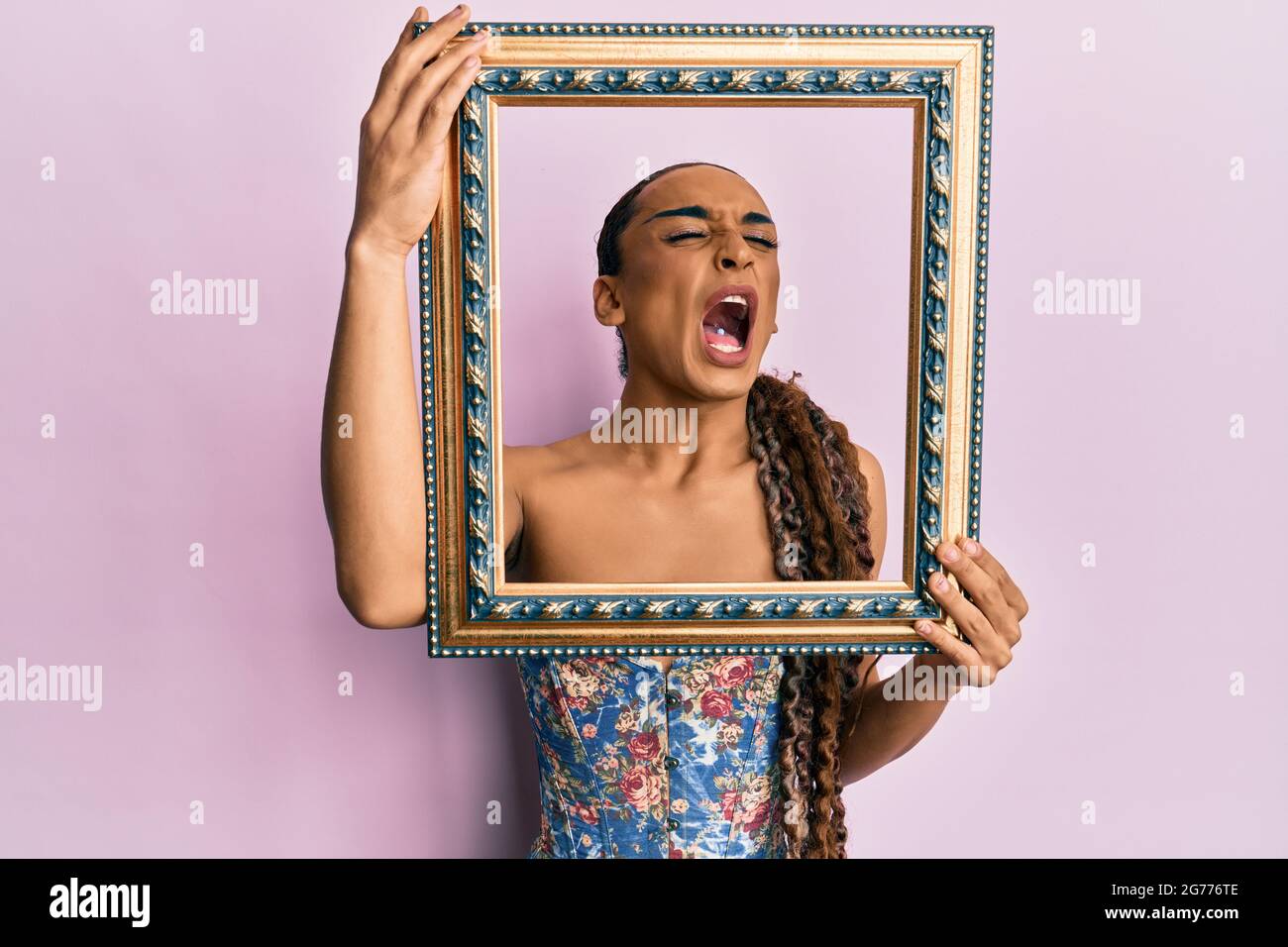 Hispanic man wearing make up and long hair holding vintage empty frame ...