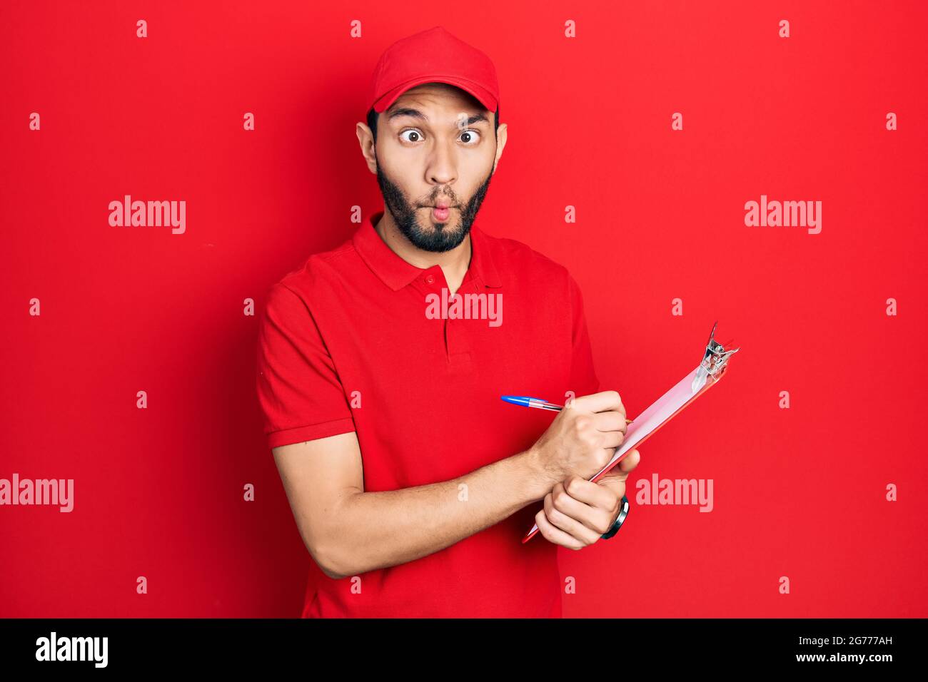 Hispanic Man With Beard Wearing Courier Uniform Holding Clipboard