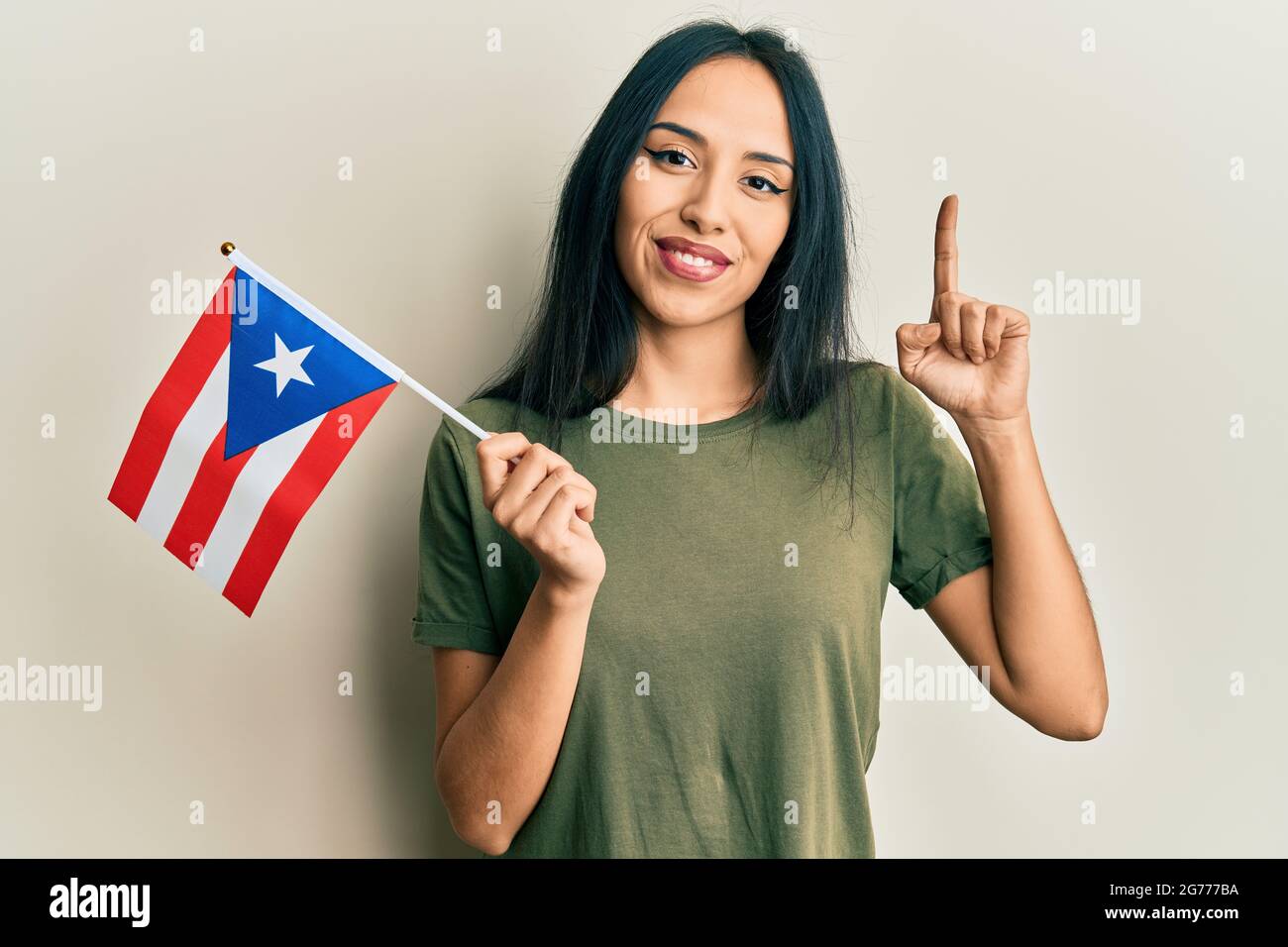 Young hispanic girl holding puerto rico flag smiling with an idea or ...