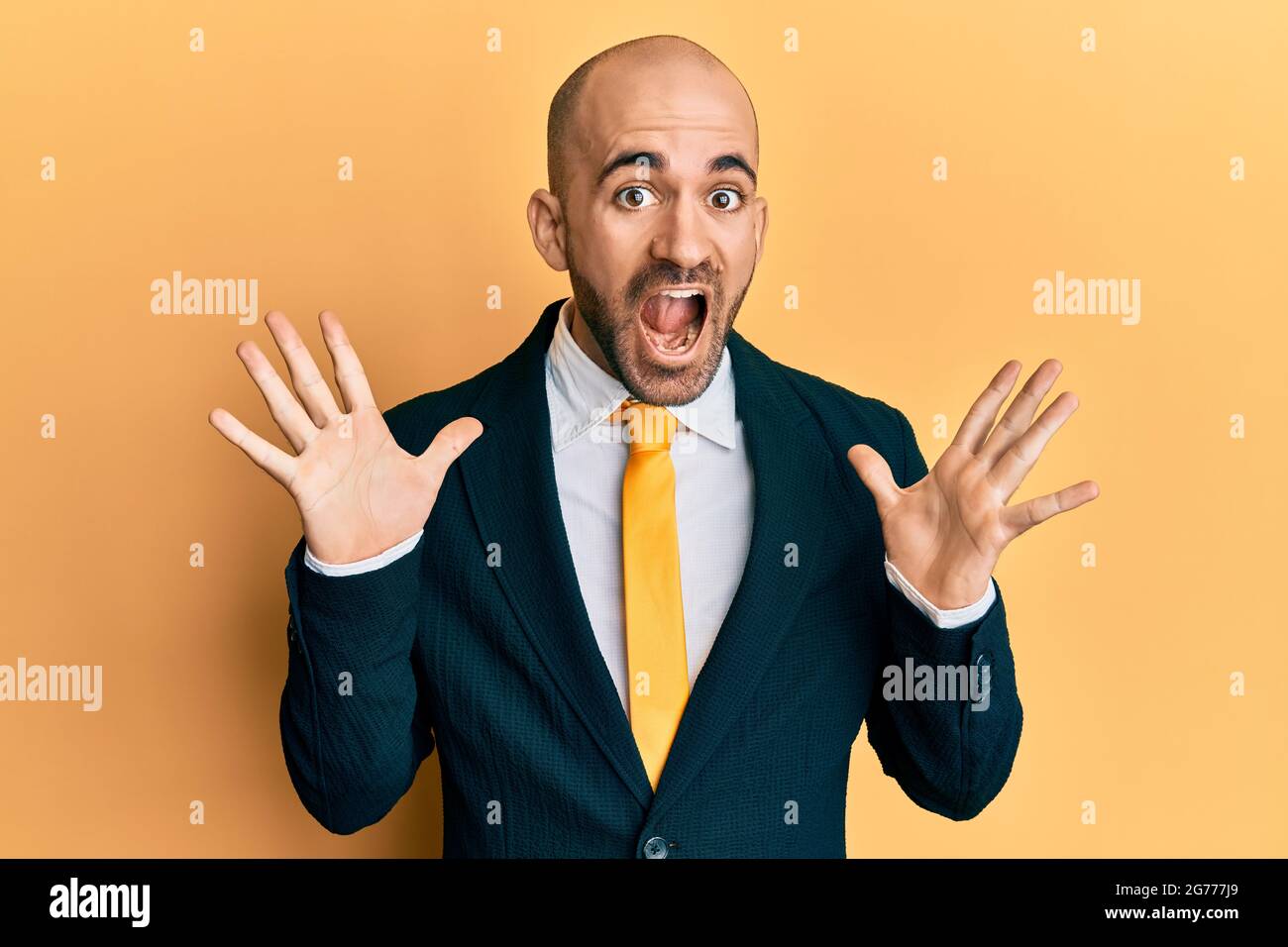 Young hispanic man wearing business suit and tie celebrating crazy and ...