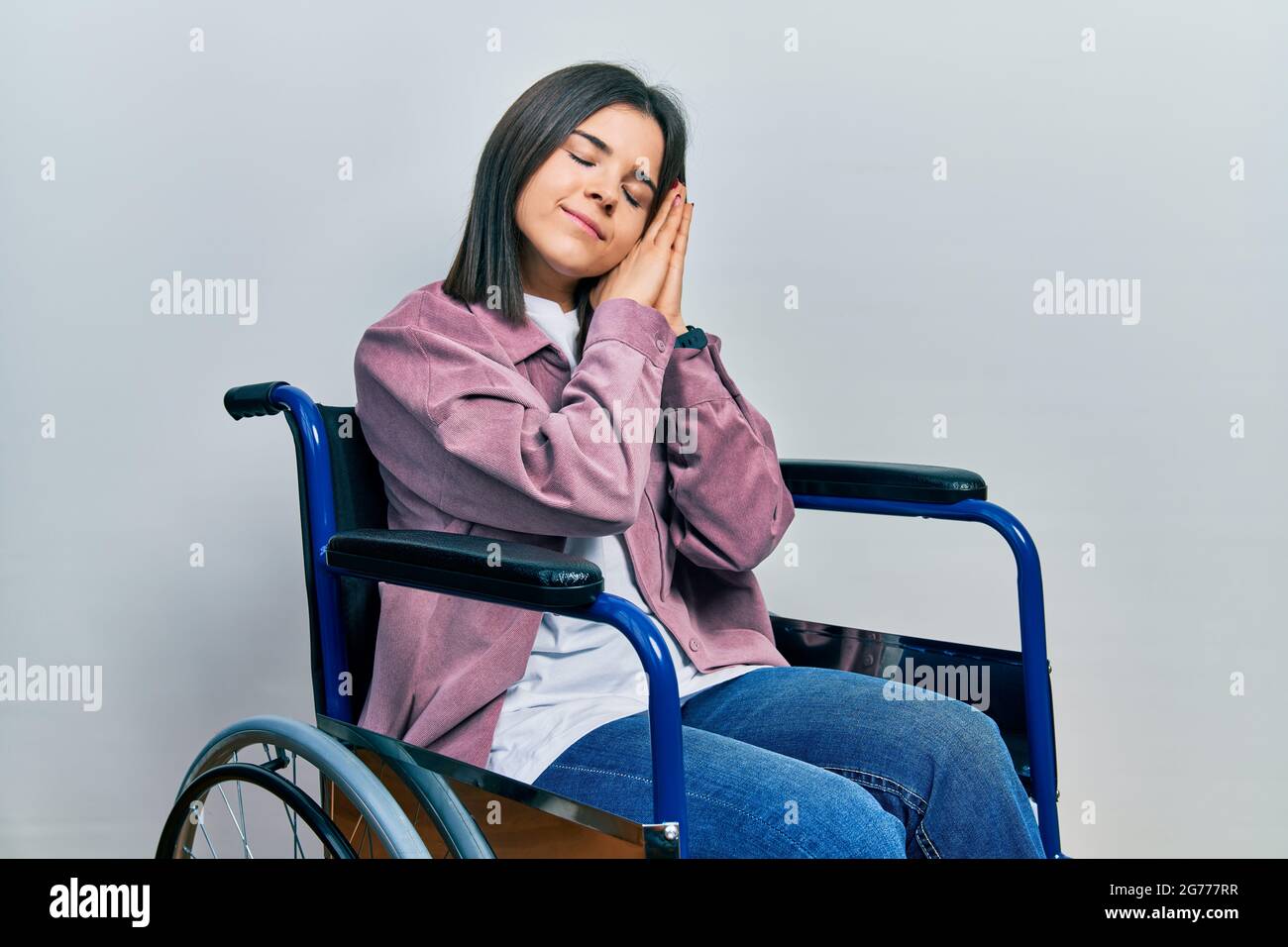 Young brunette woman sitting on wheelchair sleeping tired dreaming and ...