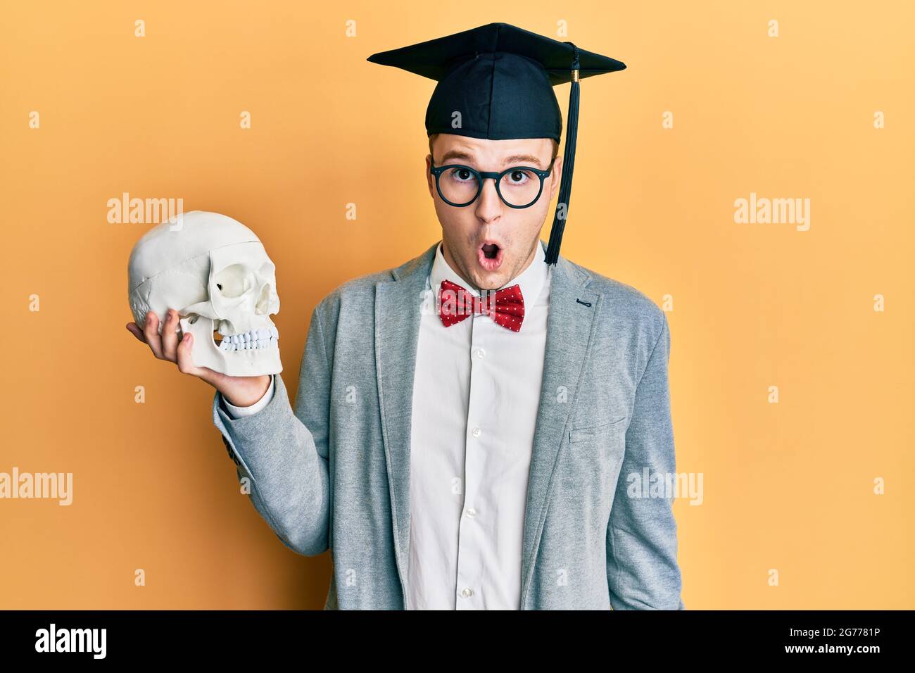 Young caucasian nerd man wearing glasses and graduation cap holding ...