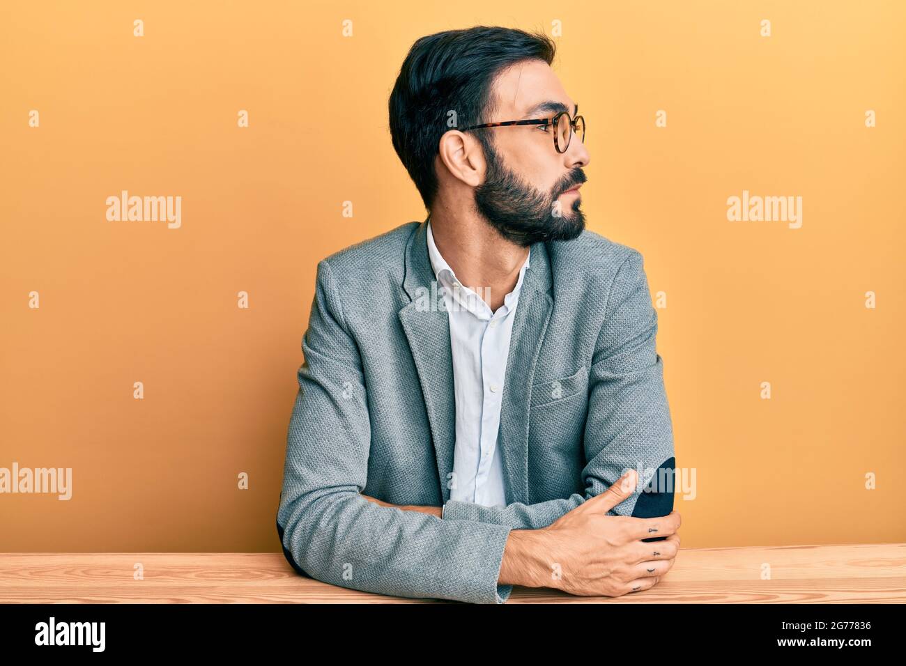 Young hispanic man working at the office looking to side, relax profile ...