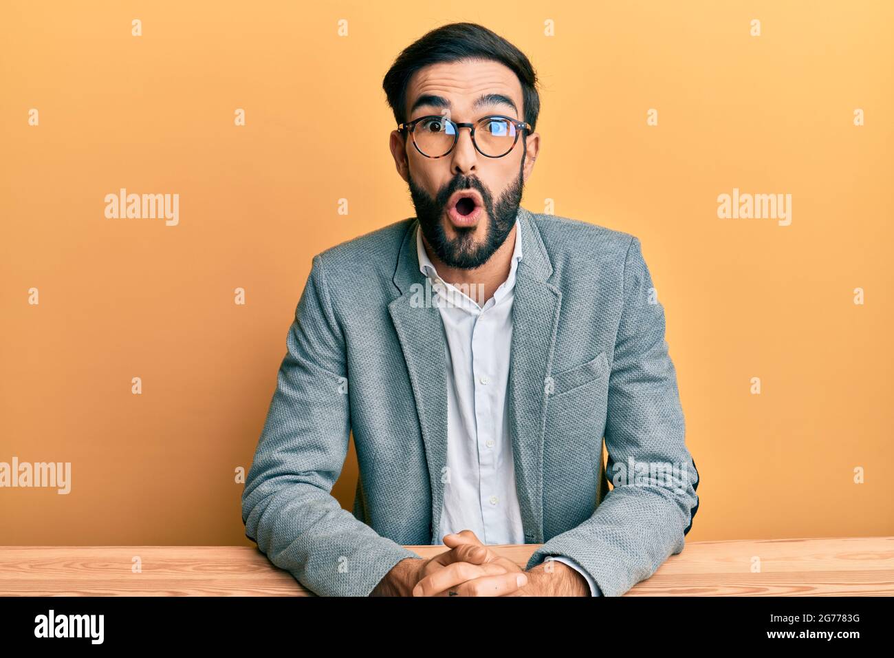 Young hispanic man working at the office afraid and shocked with ...