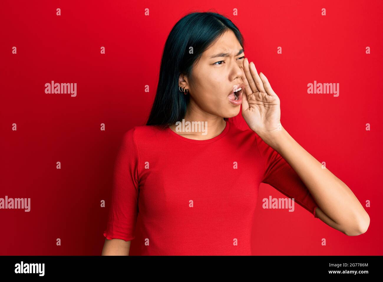 Young chinese woman wearing casual clothes shouting and screaming loud ...